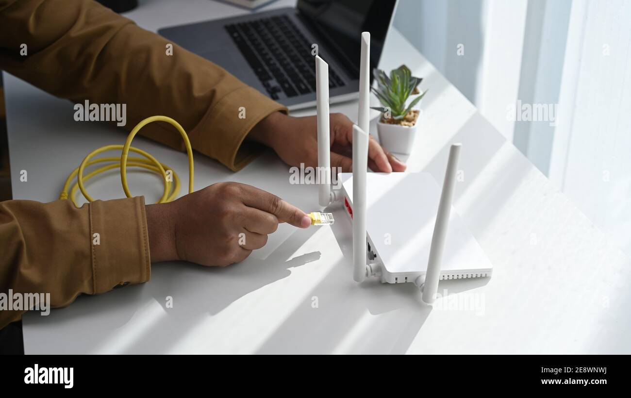Close up view of man connects the internet cable to router socket ...