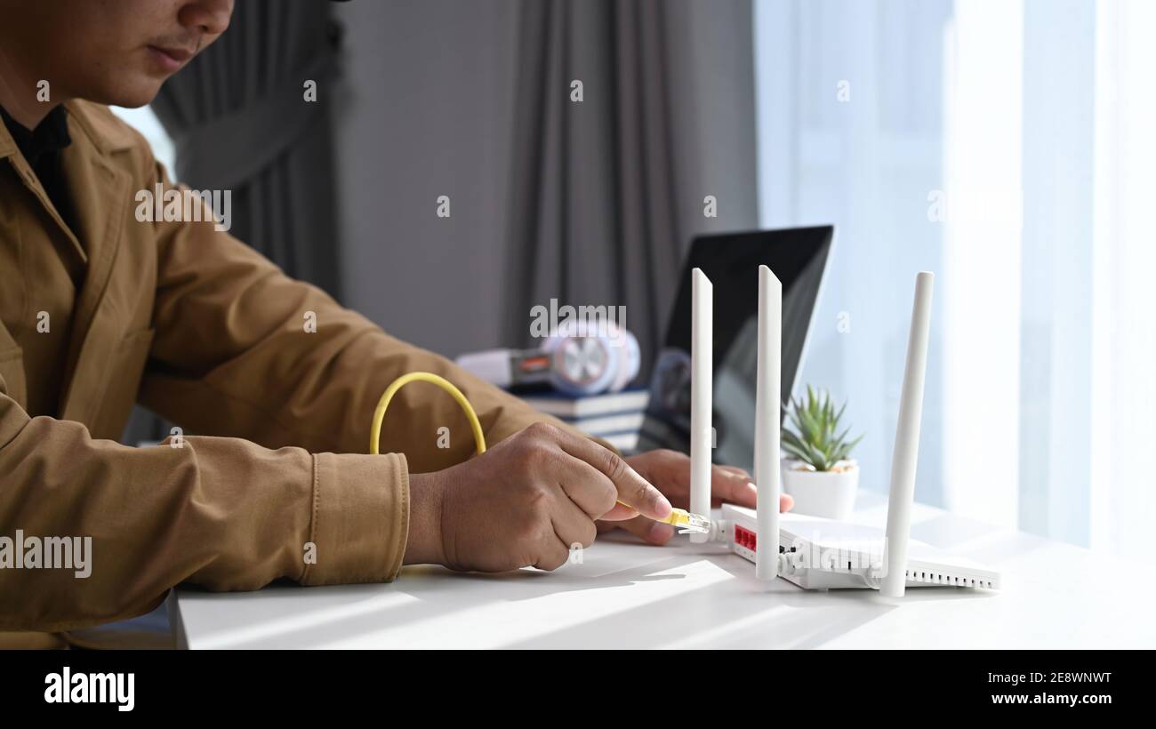 Close up view of young man connects the internet cable into router ...