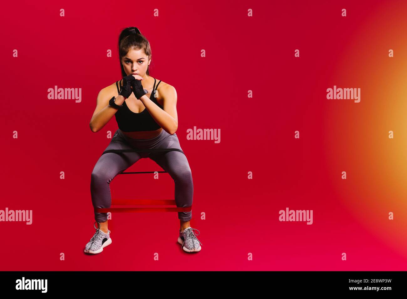 Caucasian pumped-up girl shakes leg muscles with an elastic band on a ...