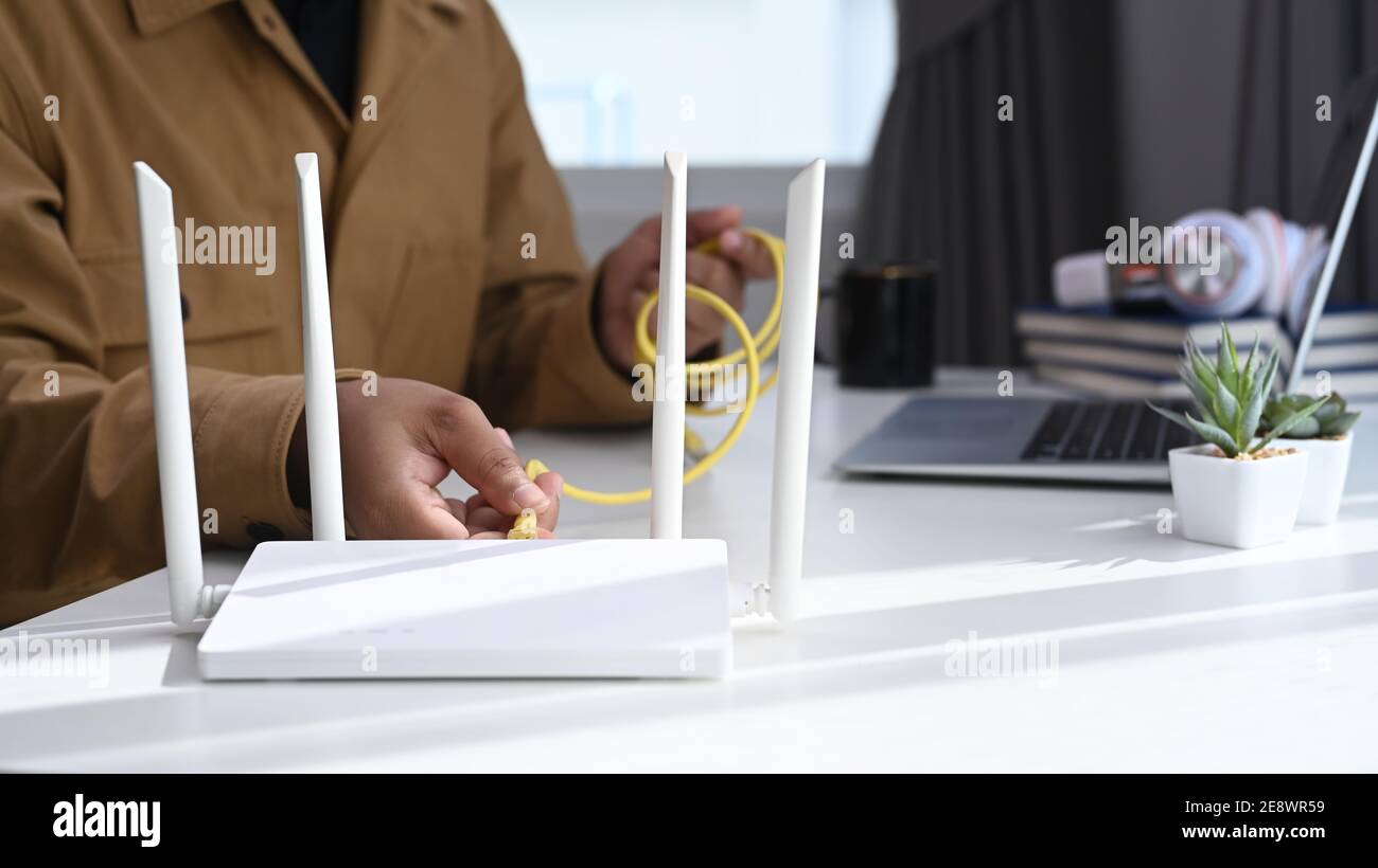 Close up view of man plugs internet cable into the router. Wireless ...