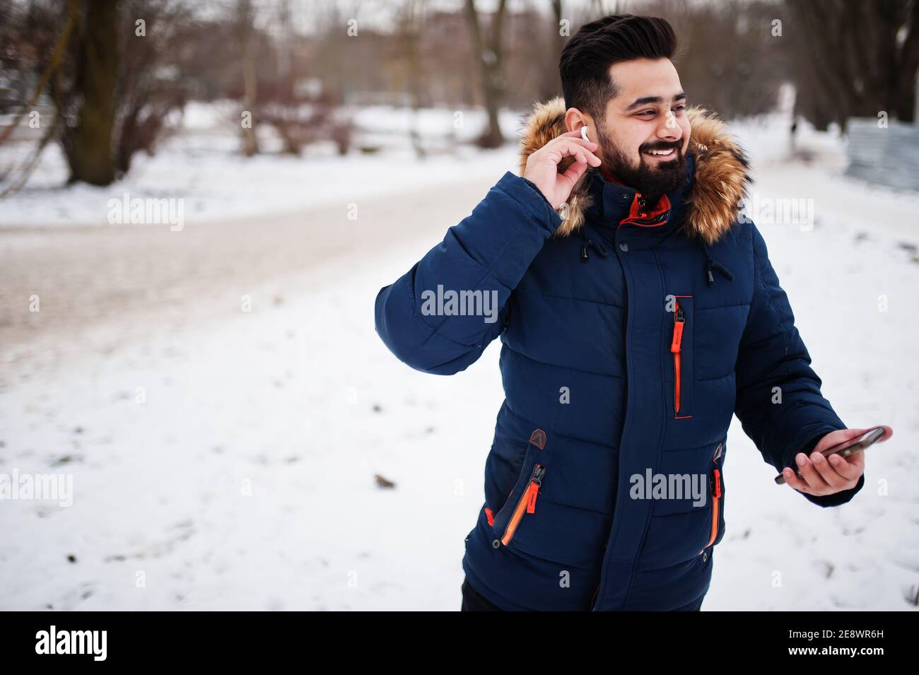 Beard indian man wear jacket in cold winter day. He speak mobile phone ...
