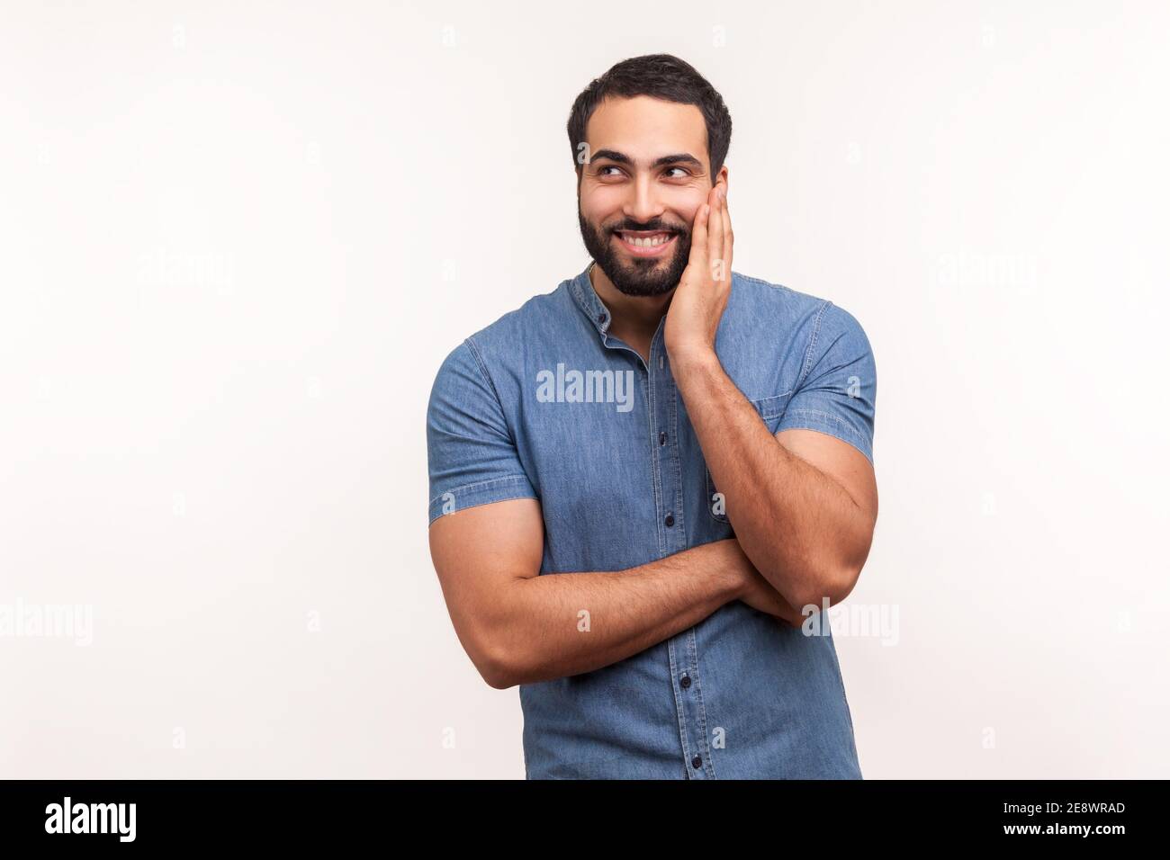 Smiling positive bearded man in blue shirt leaning head on hand ...