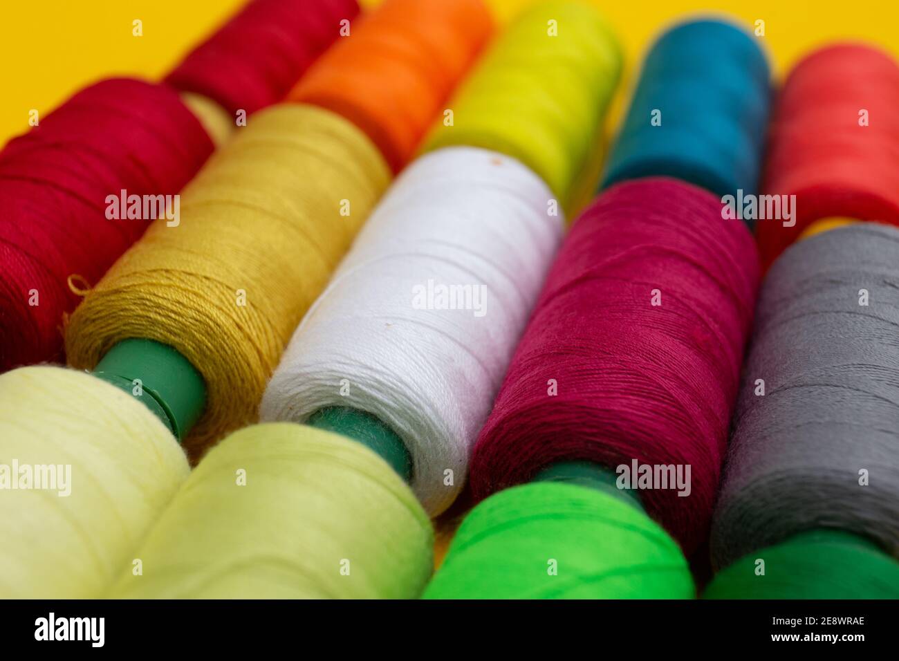 top view of Colored thread coils on yellow background, sewing, place ...