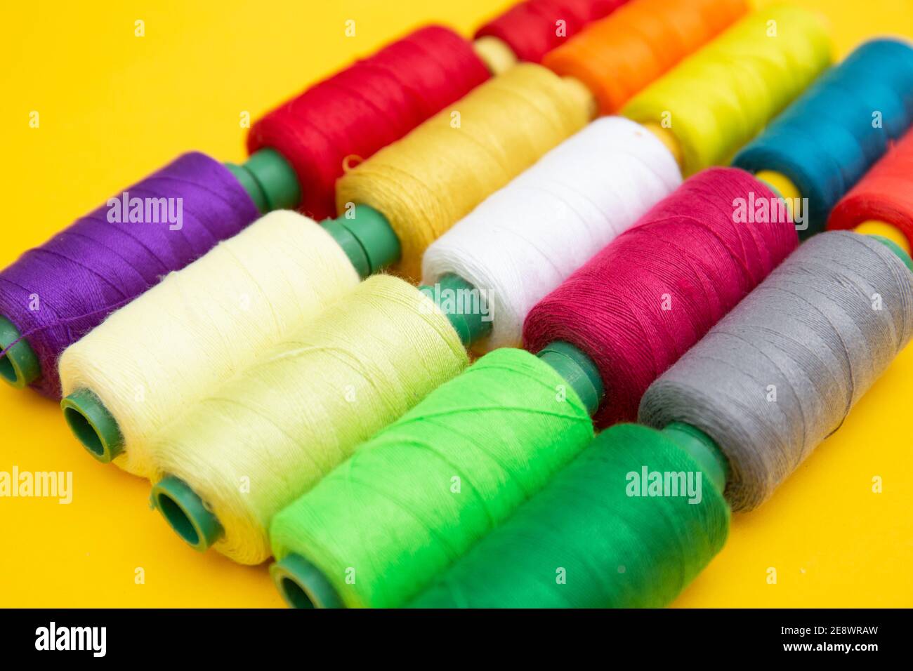 top view of Colored thread coils on yellow background, sewing, place ...