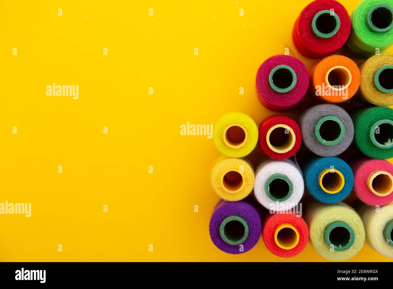 top view of Colored thread coils on yellow background, sewing, place ...