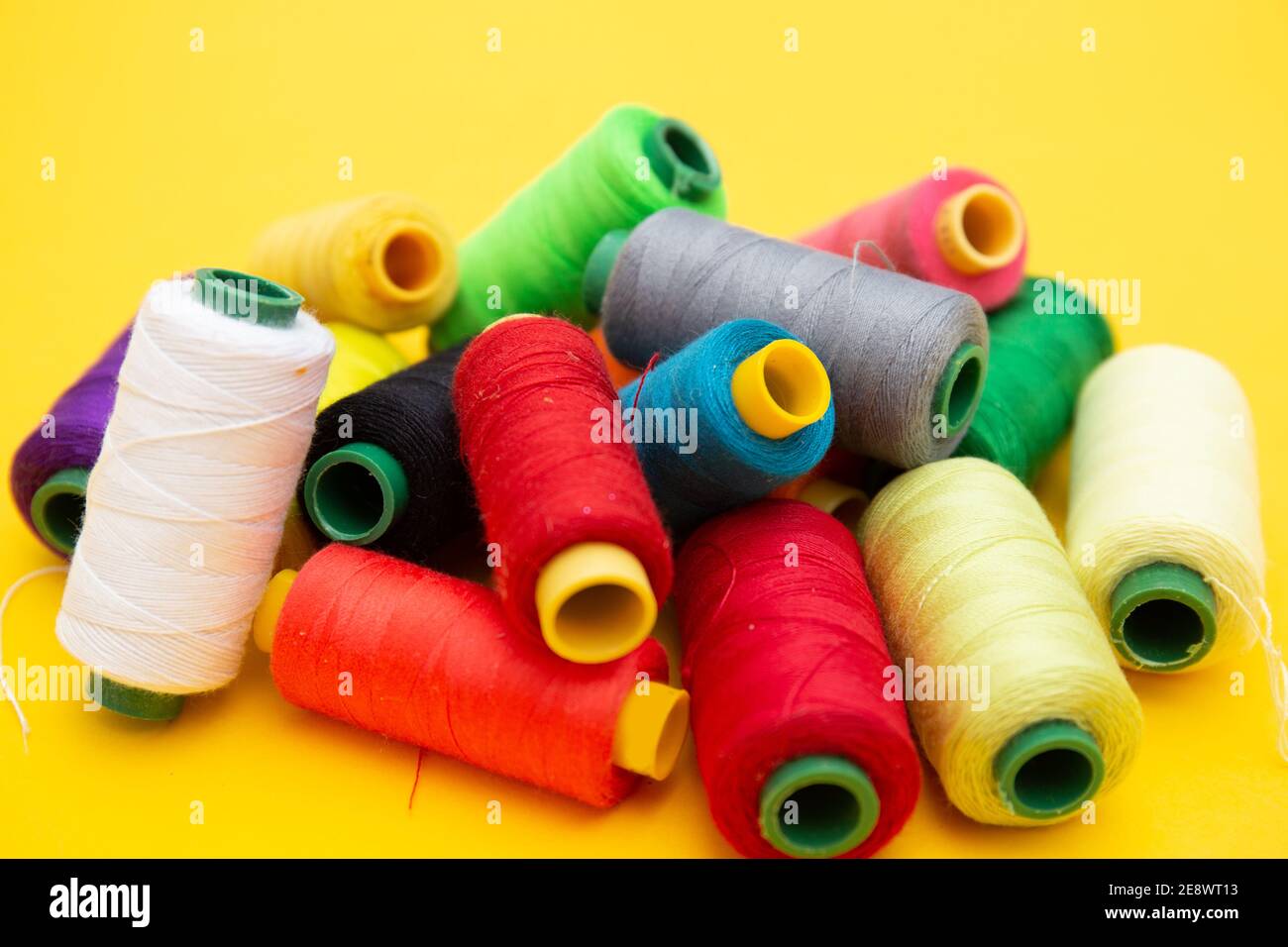 top view of Colored thread coils on yellow background, sewing, place ...