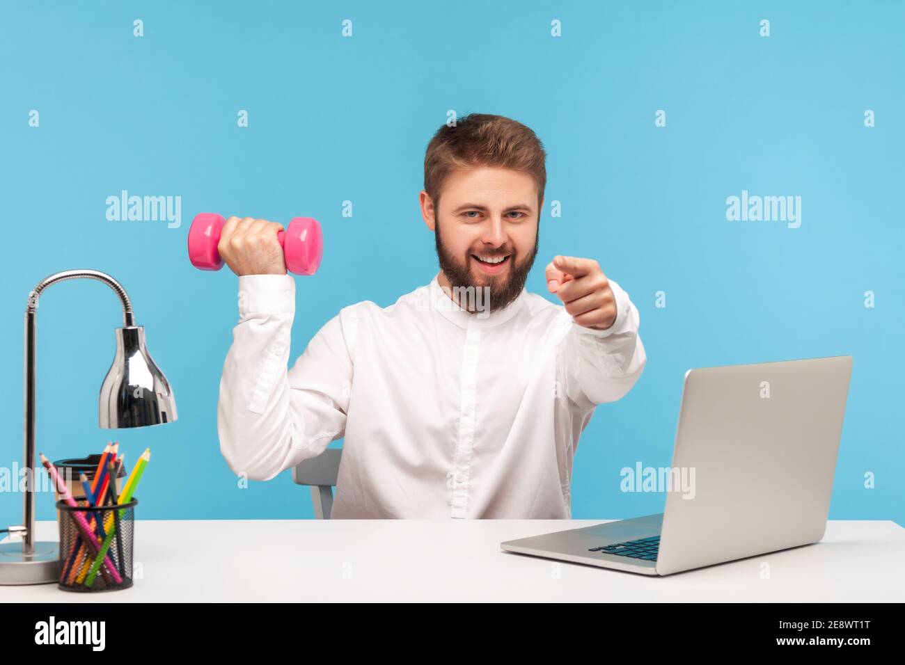 Positive healthy man office worker holding dumbbell and pointing finger ...