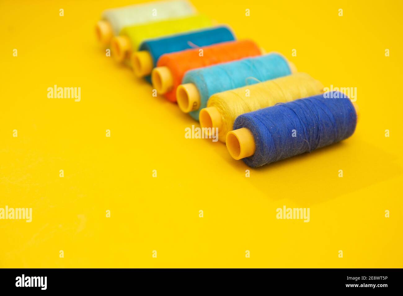 top view of Colored thread coils on yellow background, sewing, place ...