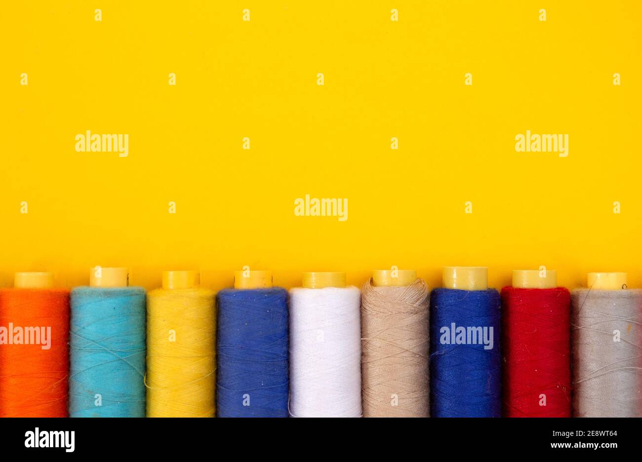 top view of Colored thread coils on yellow background, sewing, place ...