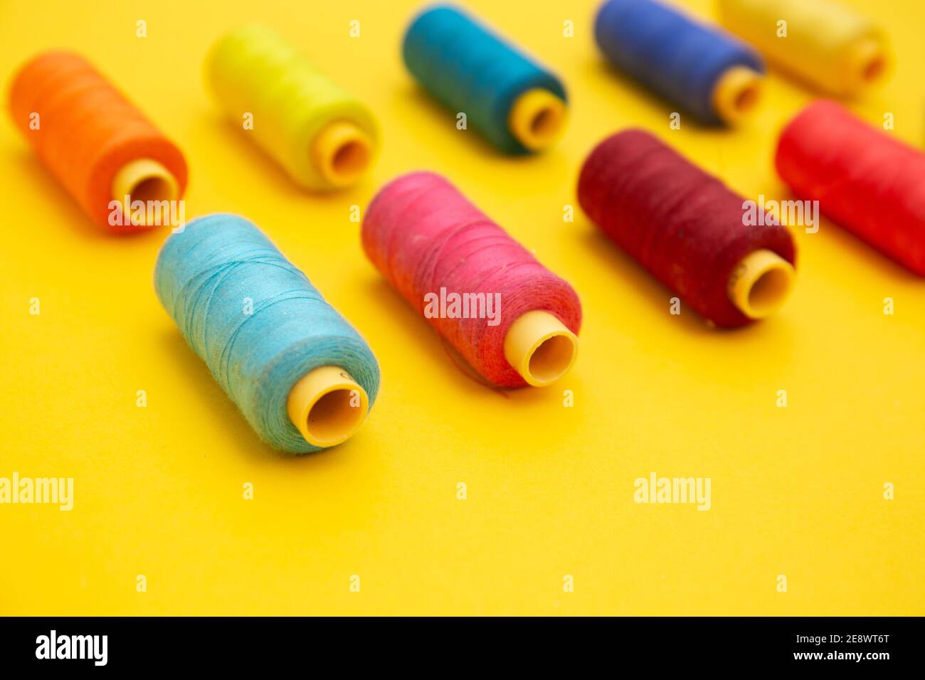 top view of Colored thread coils on yellow background, sewing, place ...