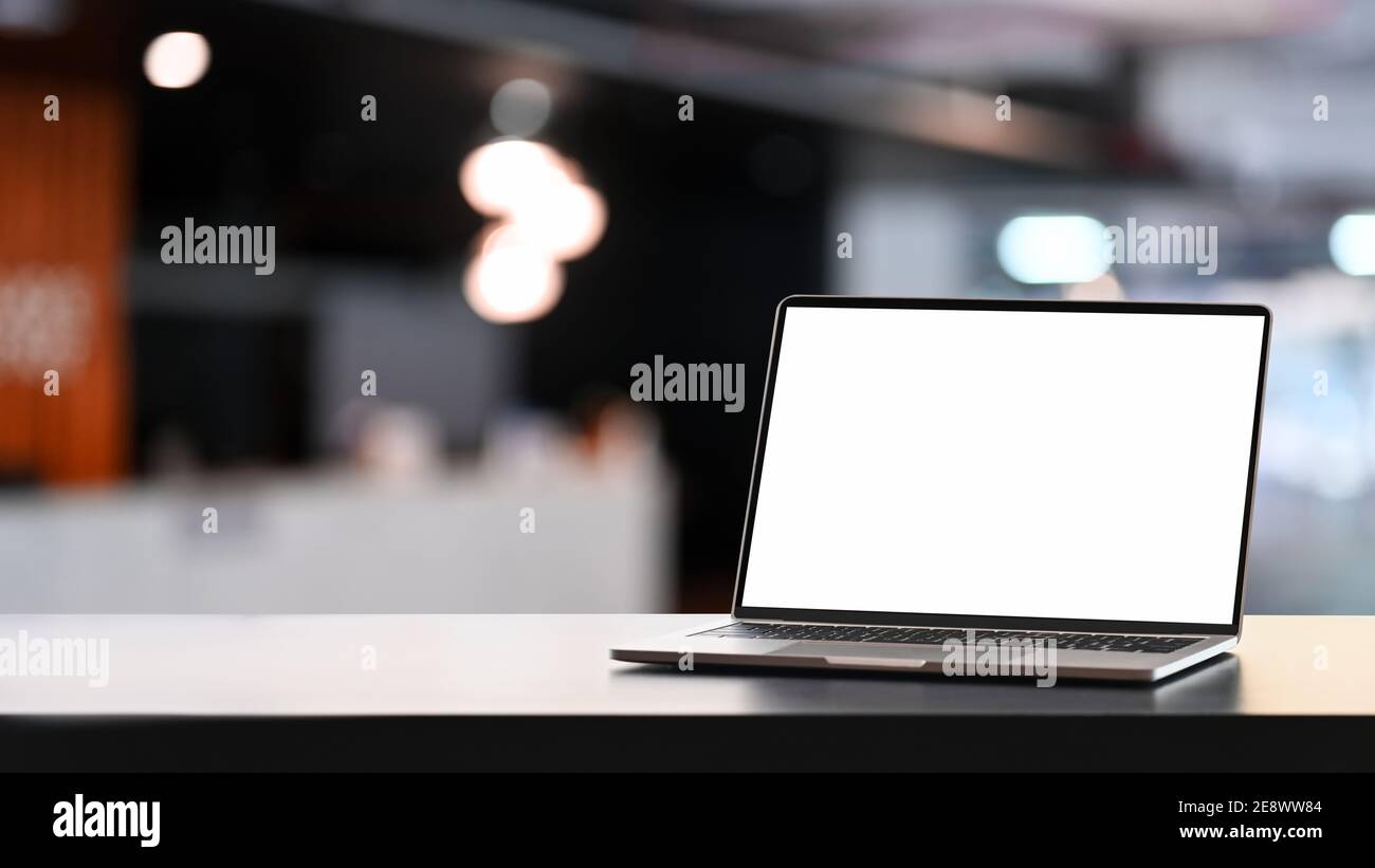 Open laptop computer with blank screen on white table and conference ...