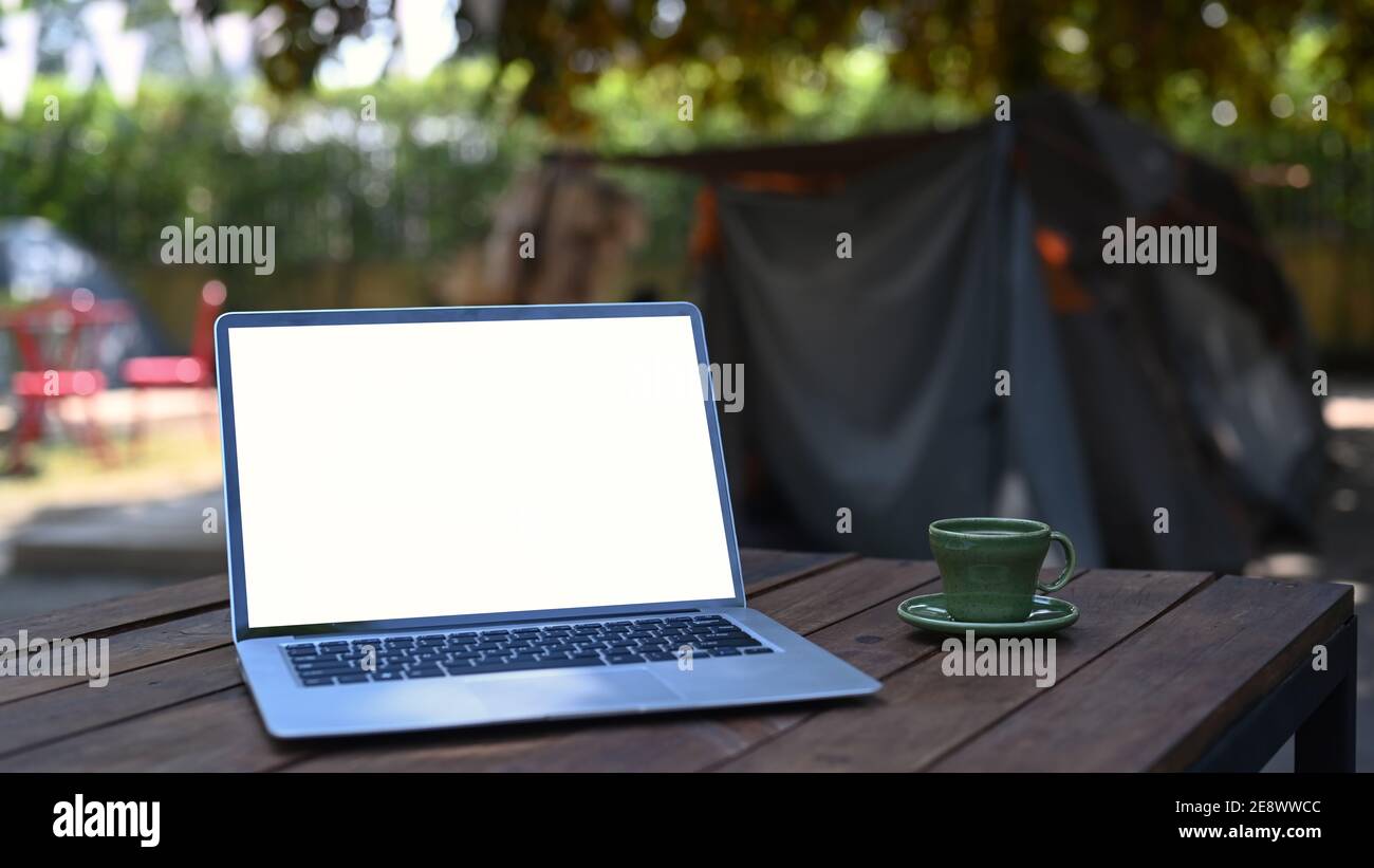 Laptop computer with blank screen and coffee cup on wooden table near ...