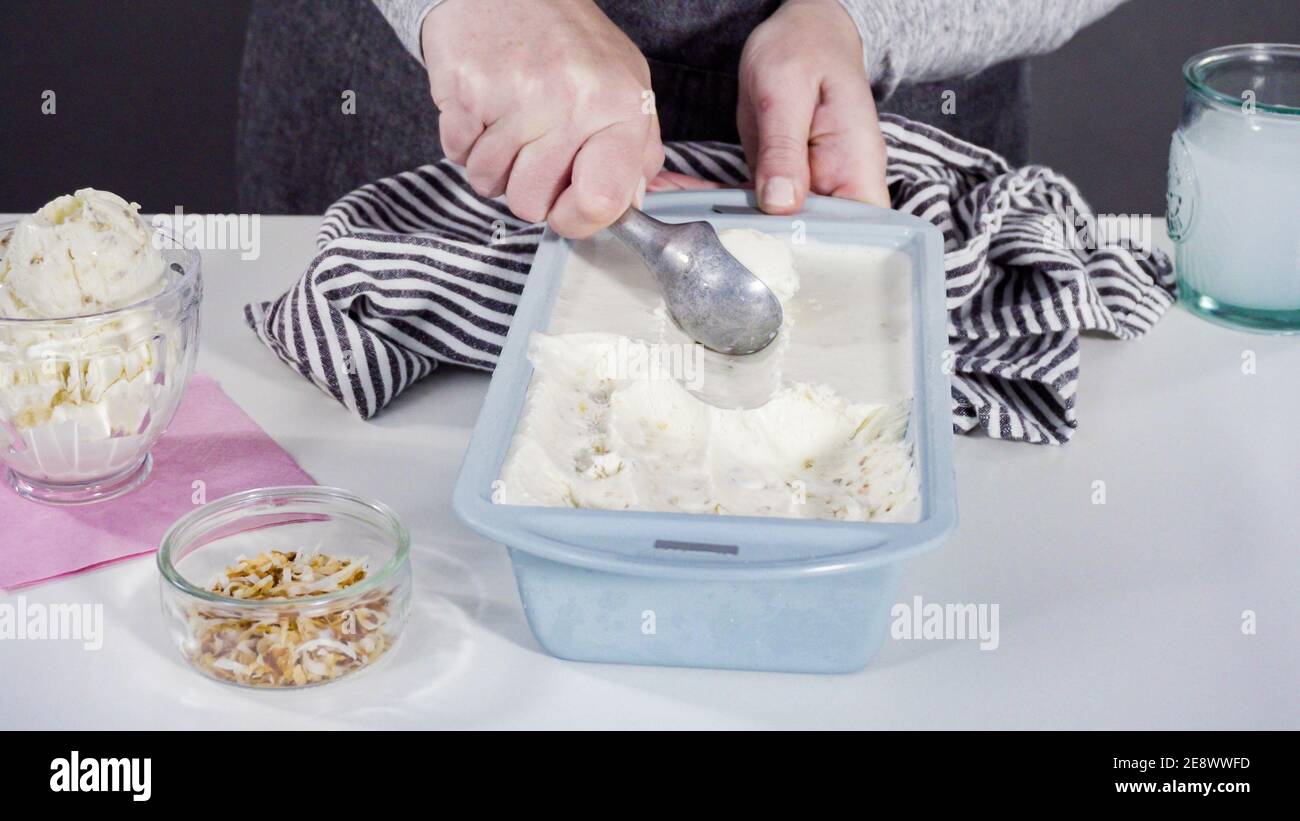 Scooping homemade coconut ice cream into a glass ice cream bowl Stock ...