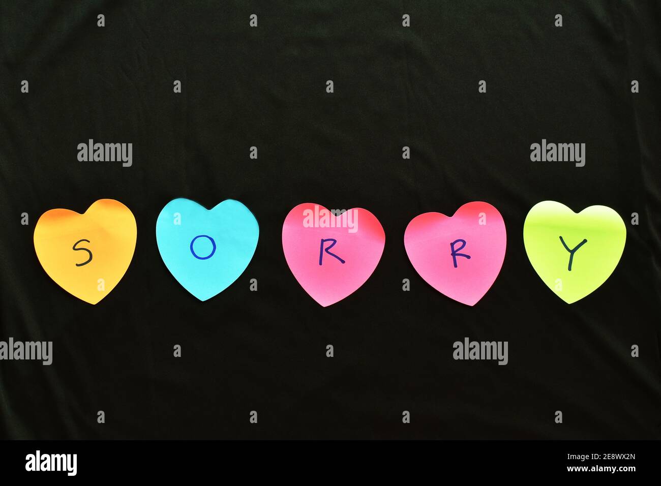colorful sticky paper note with hearth shape write sorry on black ...