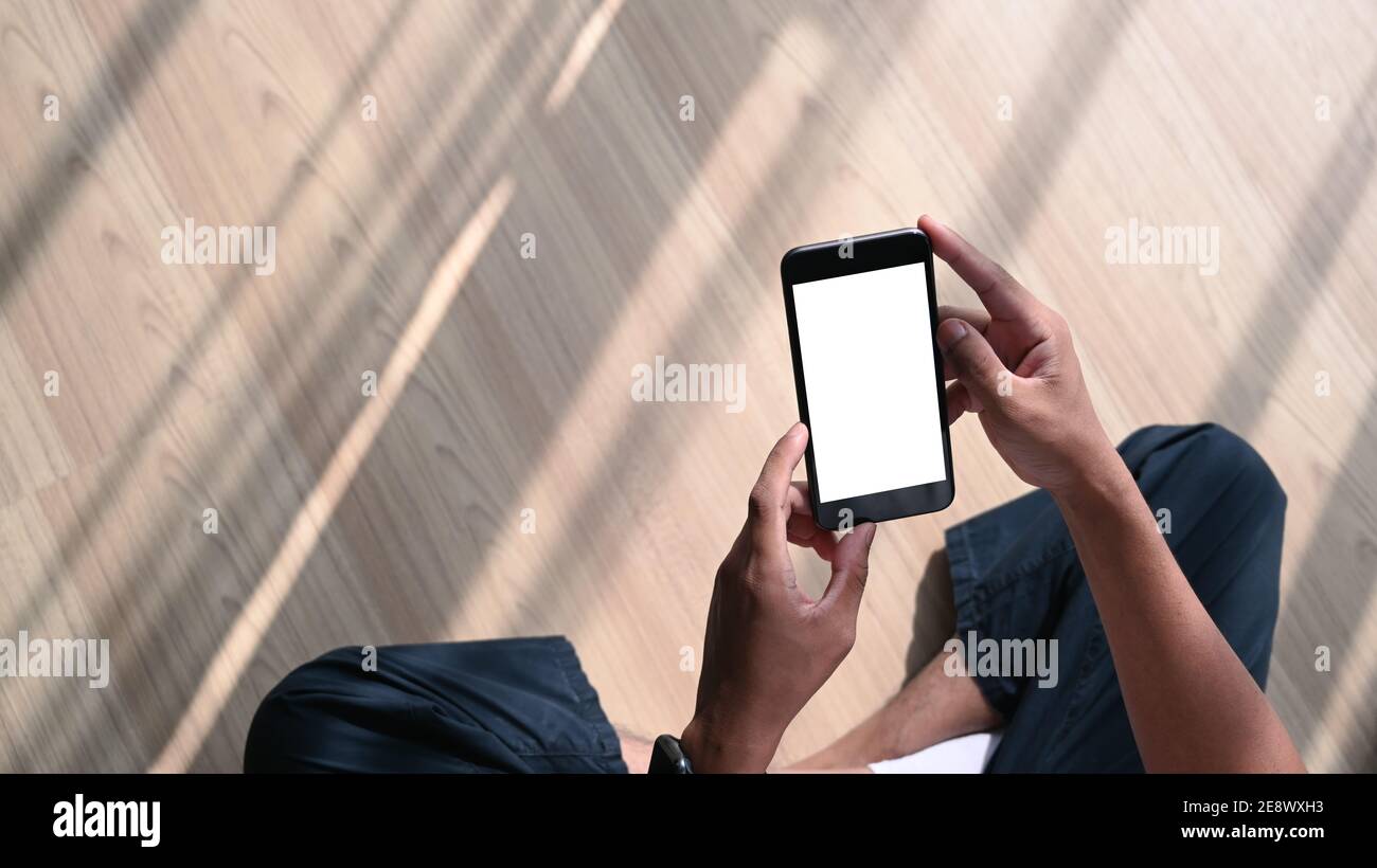 Overhead shot of man hands holding mobile phone with blank white screen ...