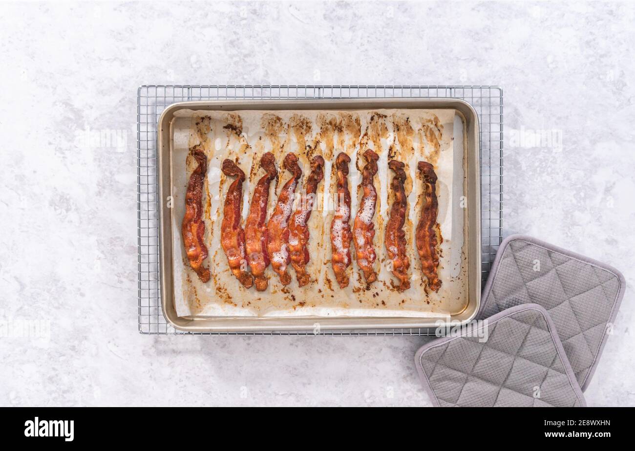 Flat lay. Cooked bacon strips on a baking sheet with white parchment ...