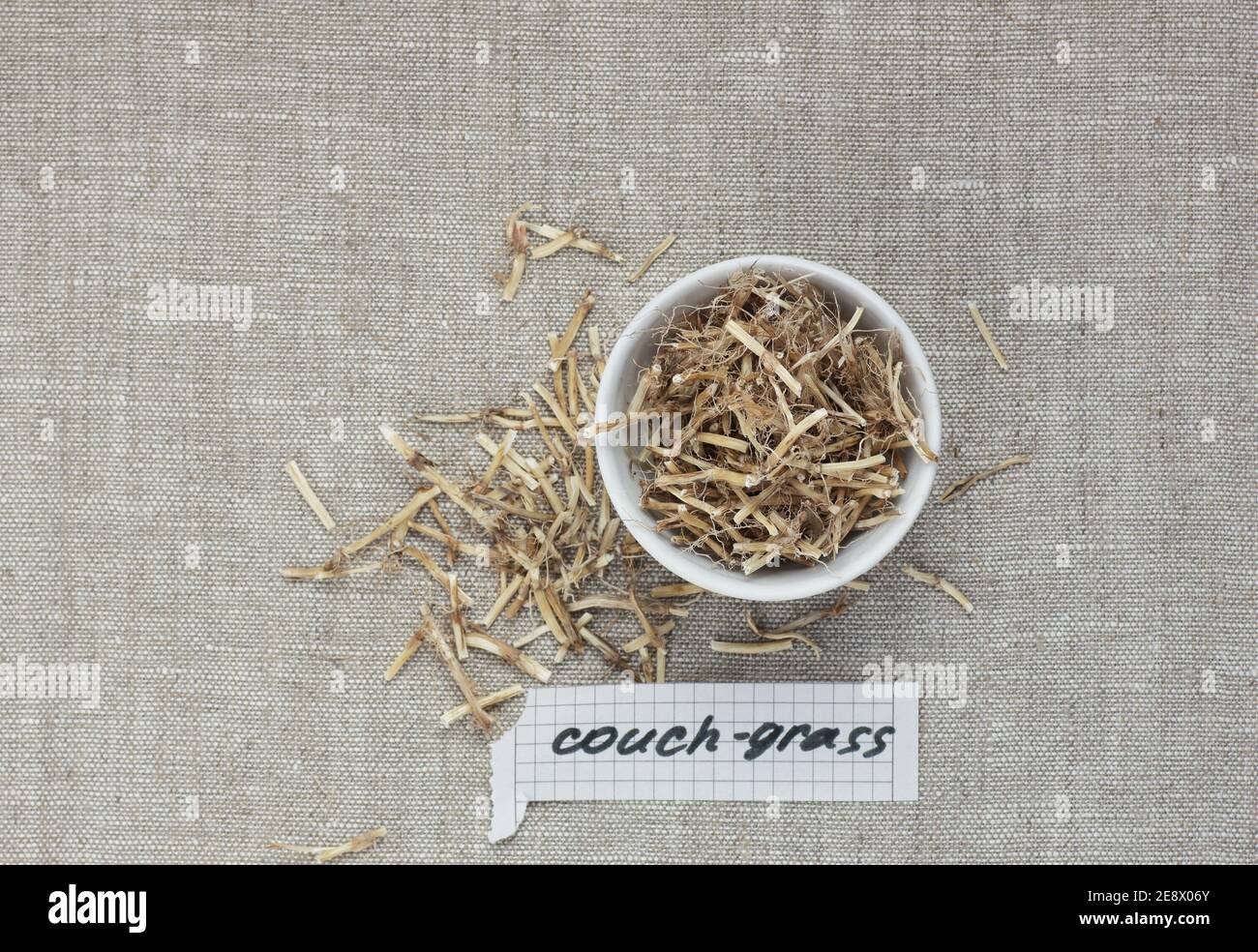 Couch-grass herbal roots in a bowl flat from above on linen textile ...