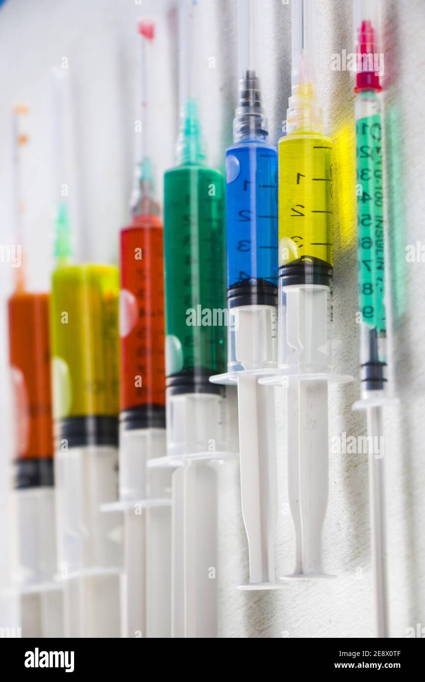Vertical shot of syringes filled with colorful chemicals in the ...