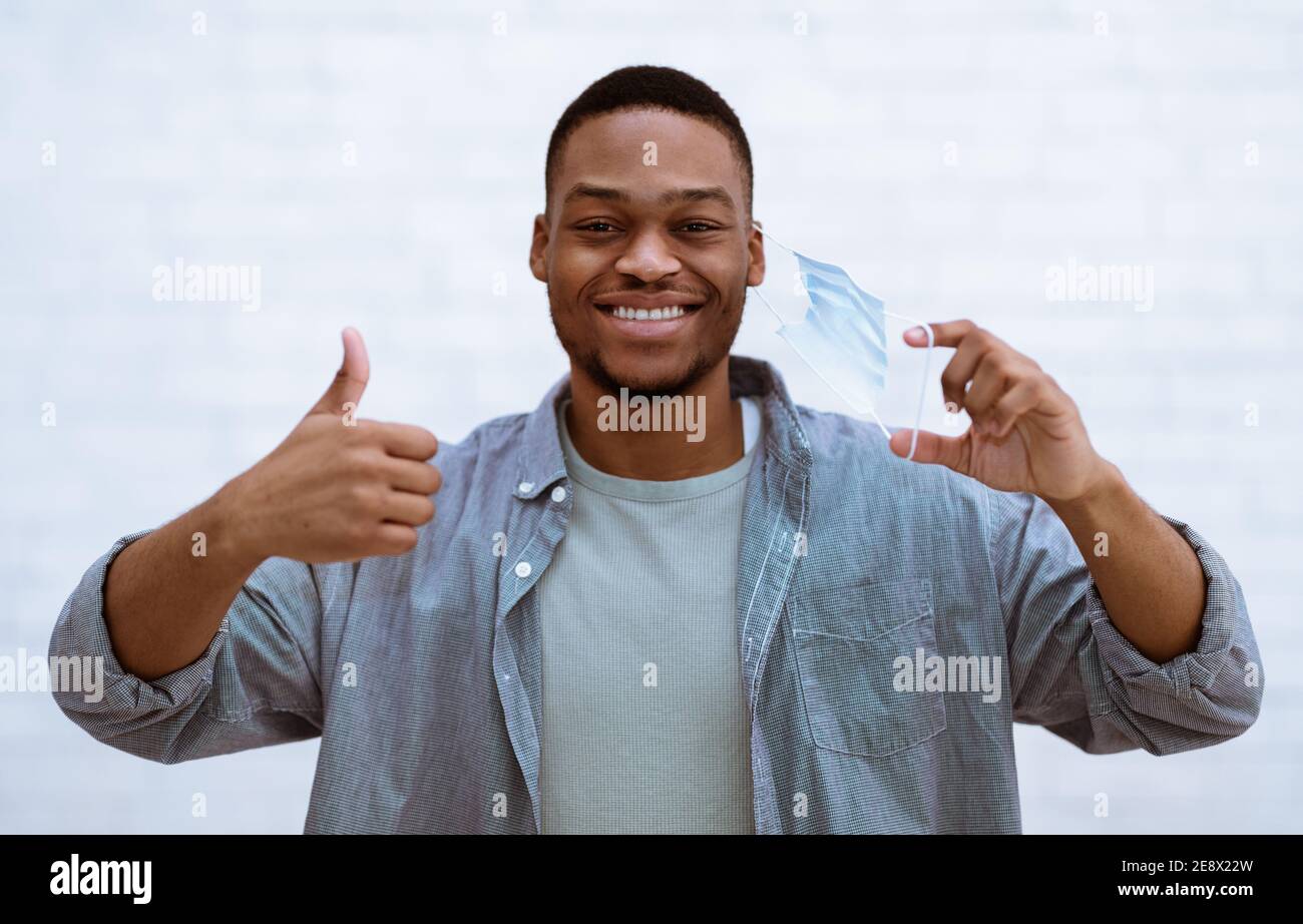 Happy Black Guy Taking Off Protective Face Mask, White Background Stock ...