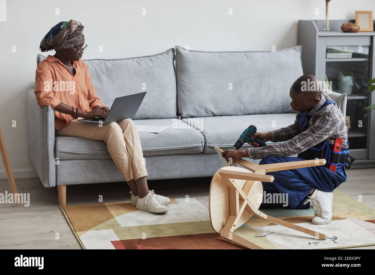 Full length portrait of African-American handyman helping young woman ...