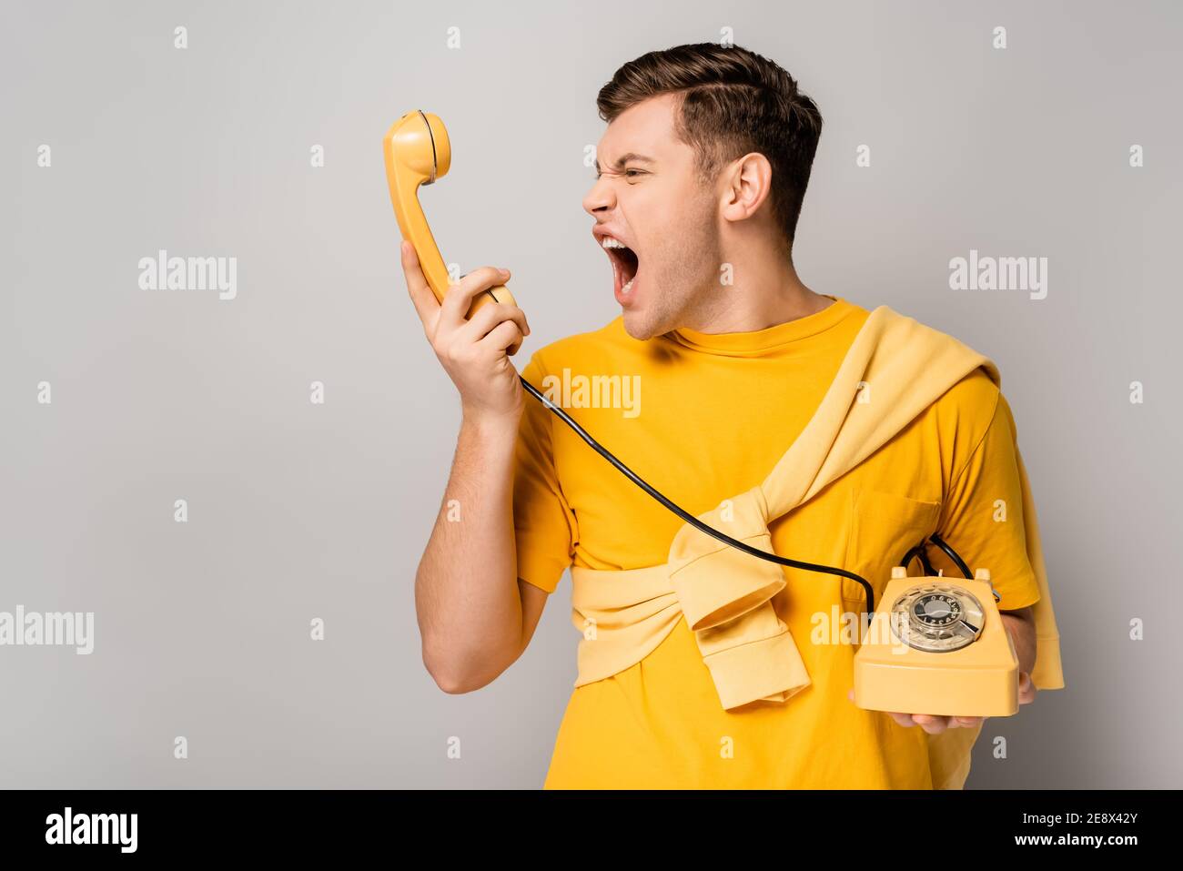Angry man screaming at telephone handset on grey background Stock Photo ...