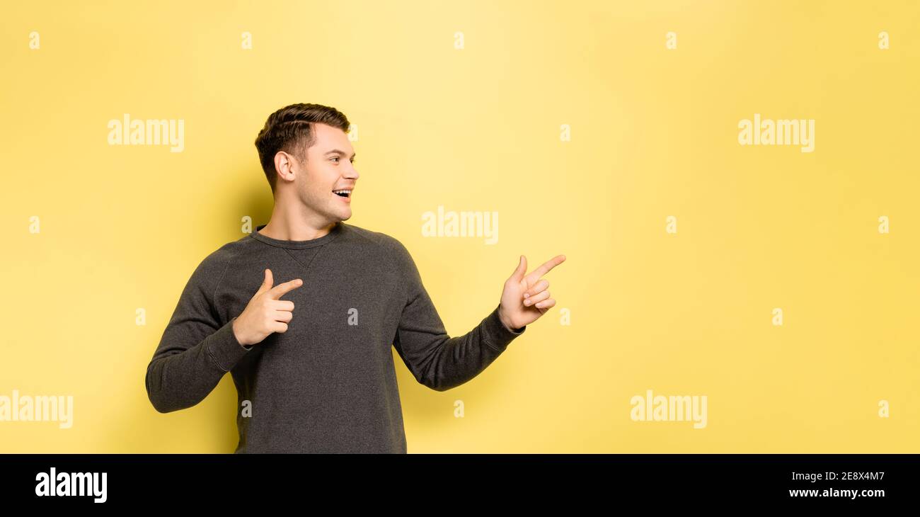 Young man pointing with fingers on yellow background, banner Stock ...