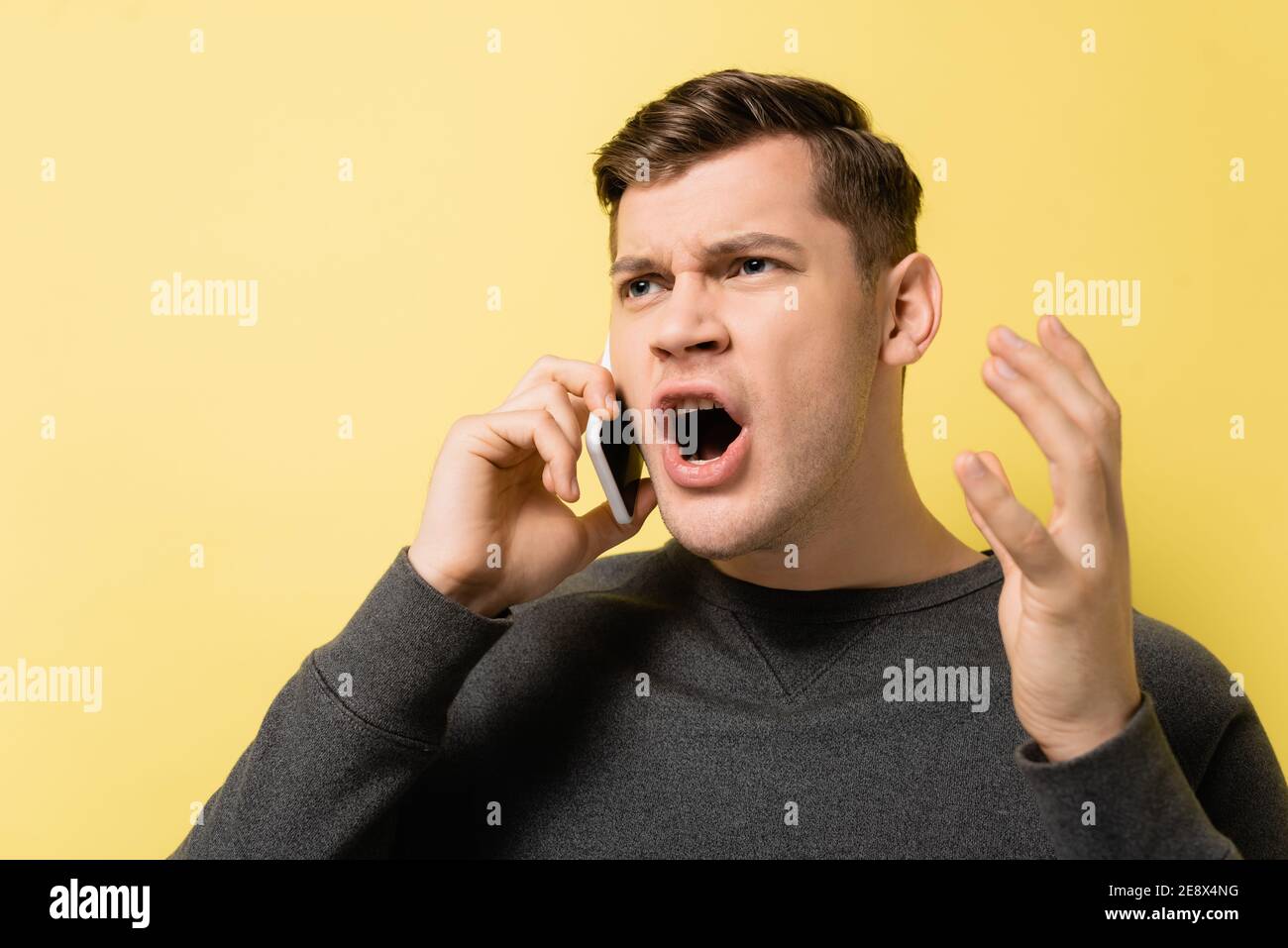 Embarrassed man talking on smartphone on yellow background Stock Photo ...
