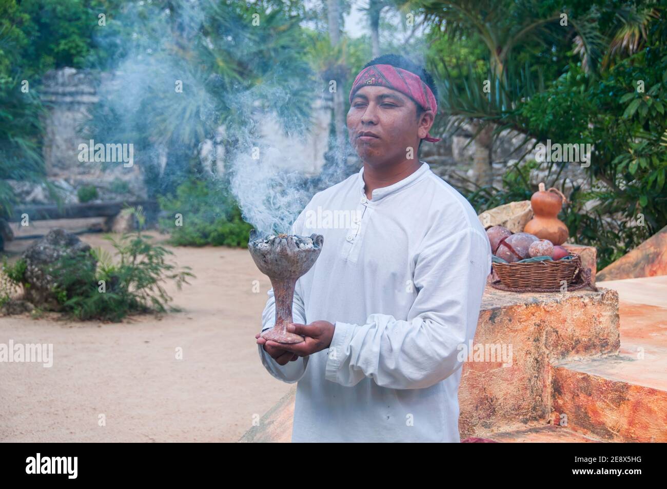 A young Mayan Man with a lit brazier, in the background a ceremonial ...