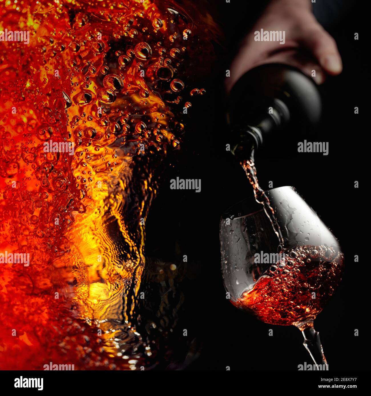 Pouring brandy in a glass goblet. Black background with copy space ...