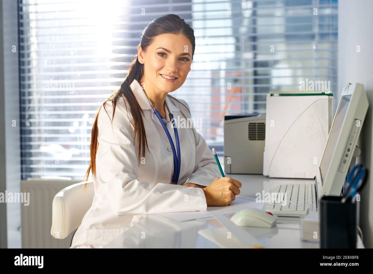 female doctor using pc computer while sitting at work place, posing at ...