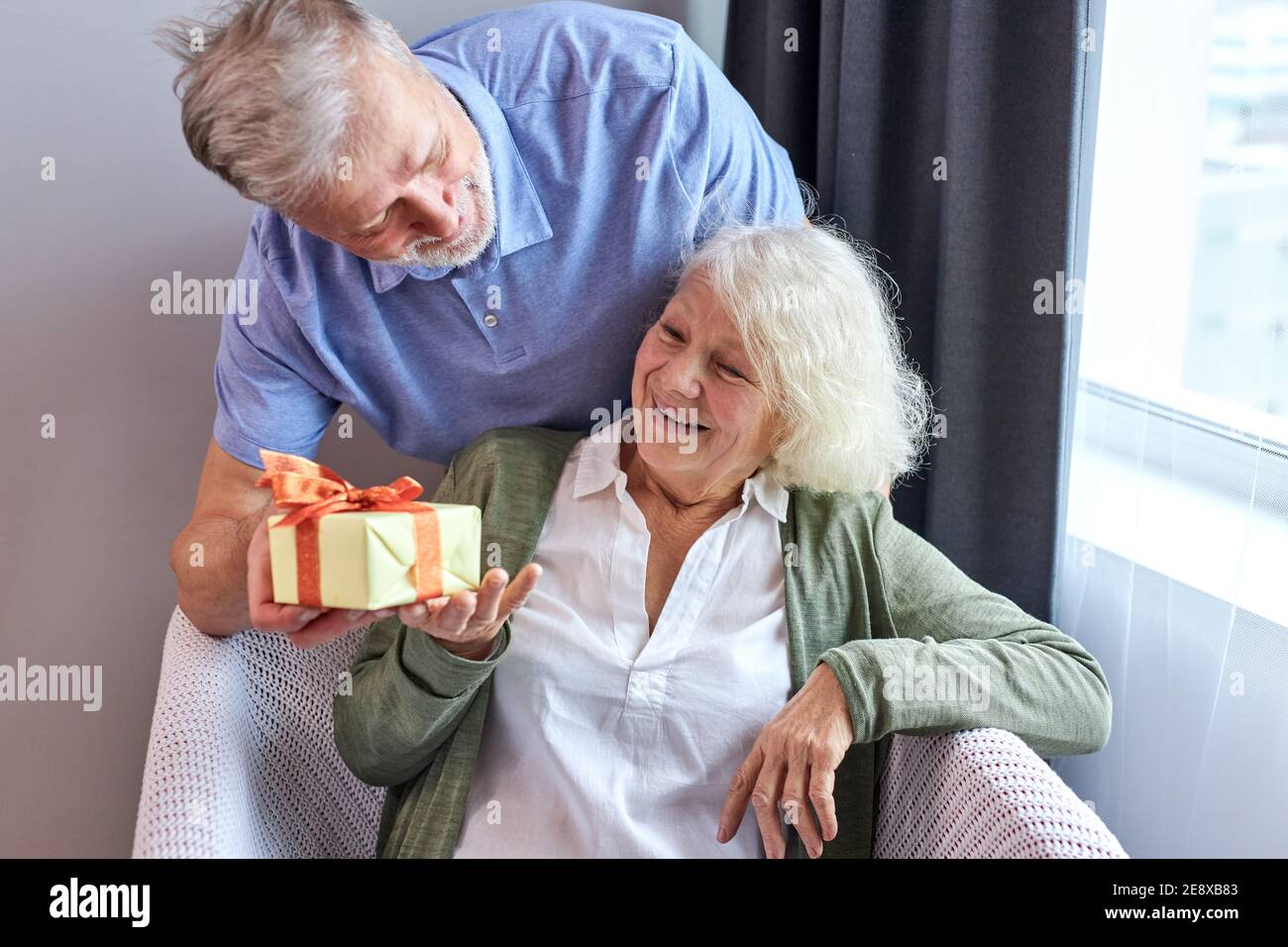 senior female person with satisfied face getting present box by her nic ...