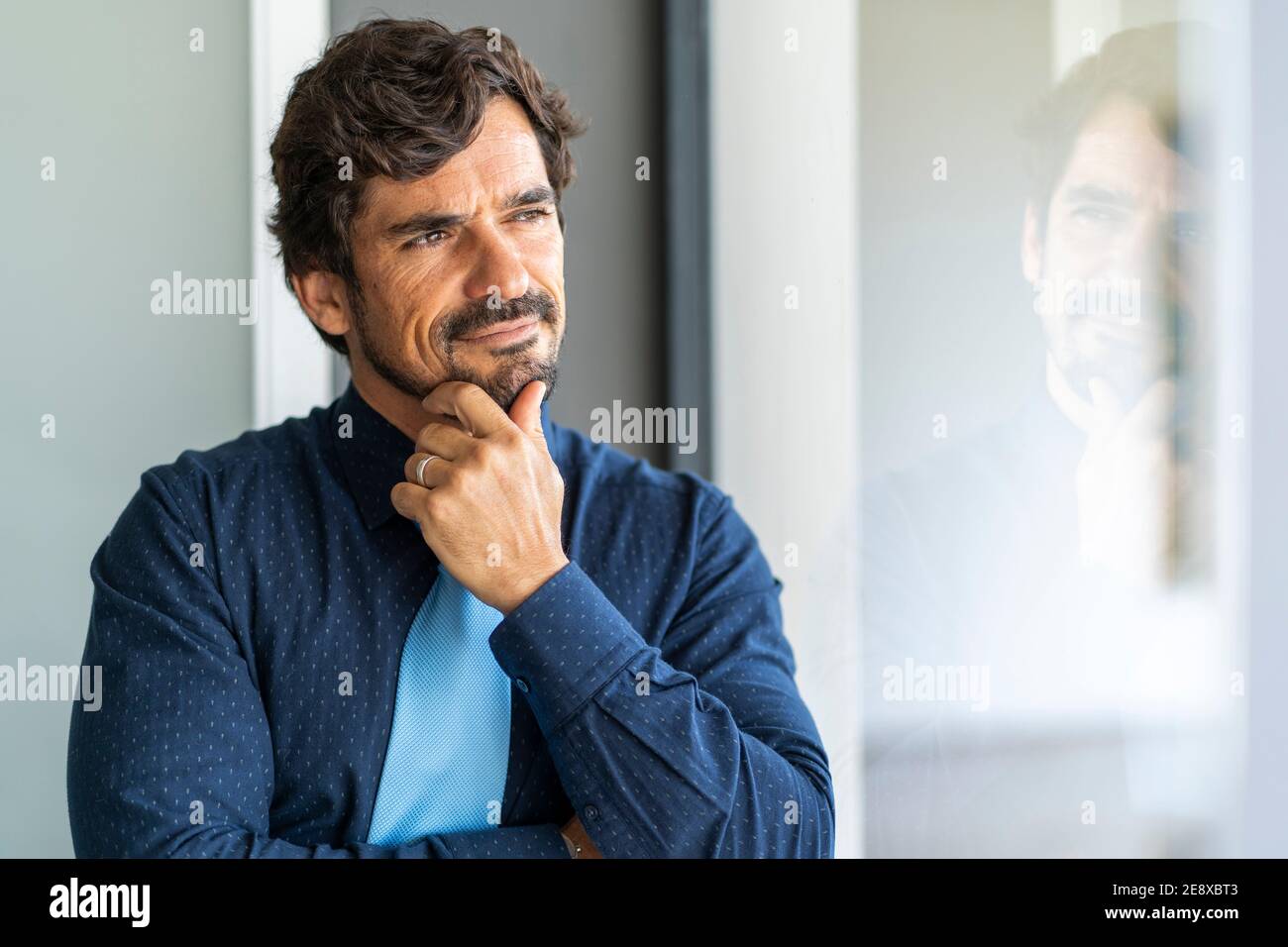 Businessman with hand on his chin looking through the window ...