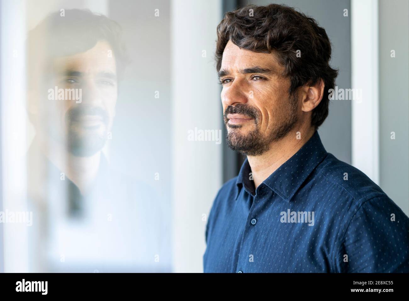 Casual man looking through window. Successful male portrait at the ...