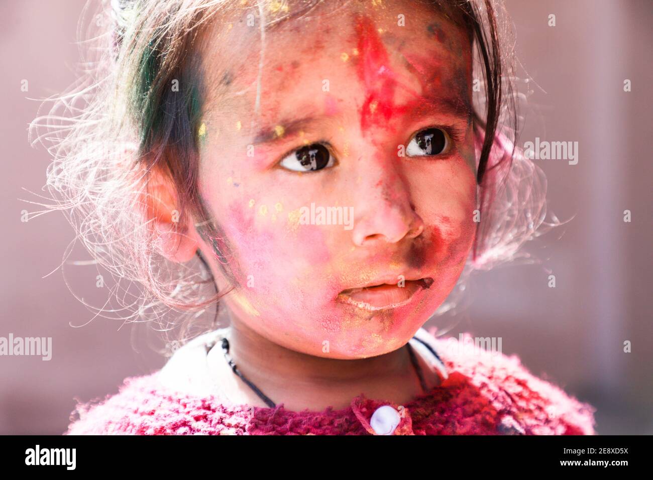 portrait of Kid face full of color while playing with color during holi ...