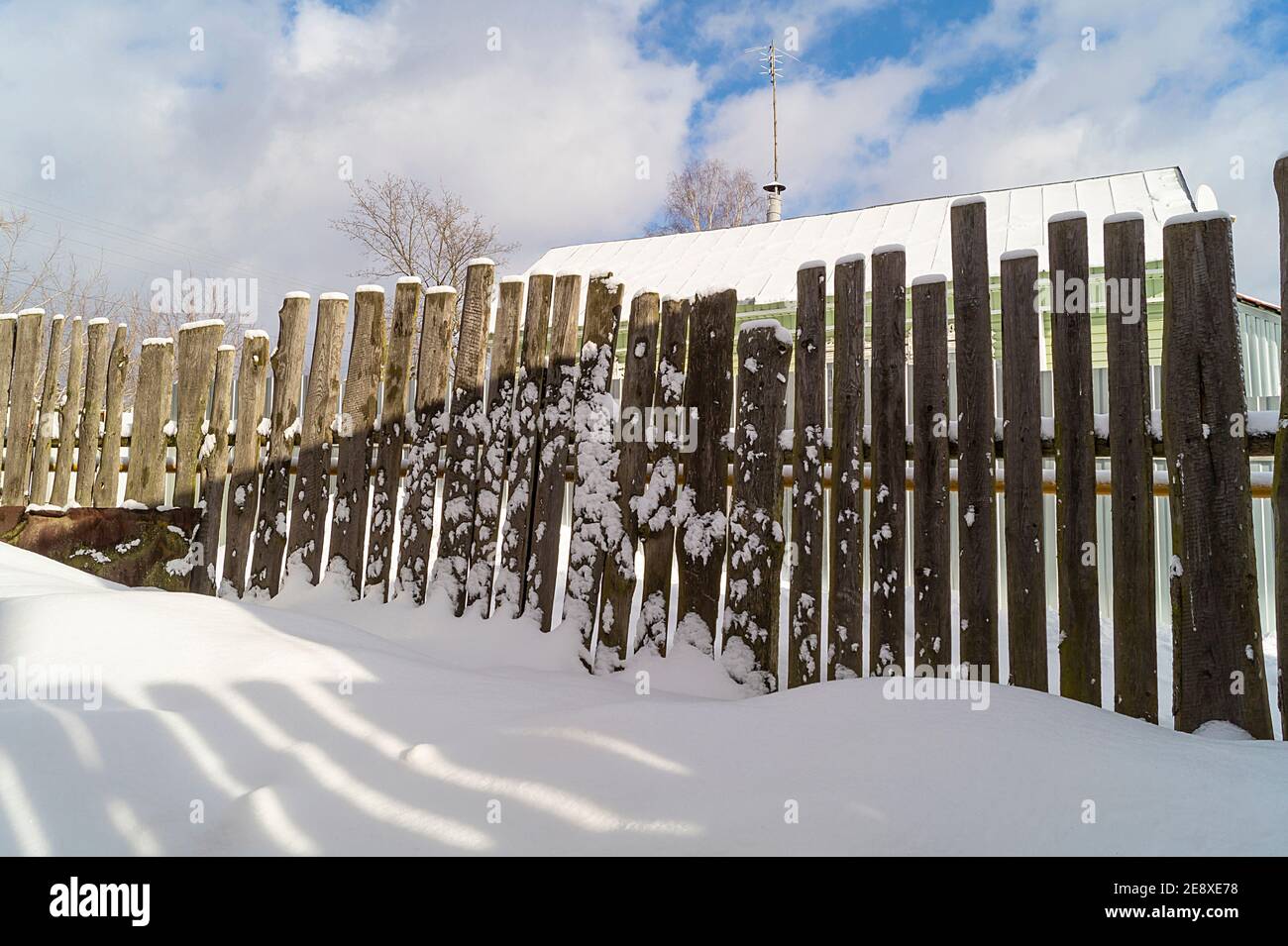 . The Winter landscape in village with wooden fence. Old fence on ...