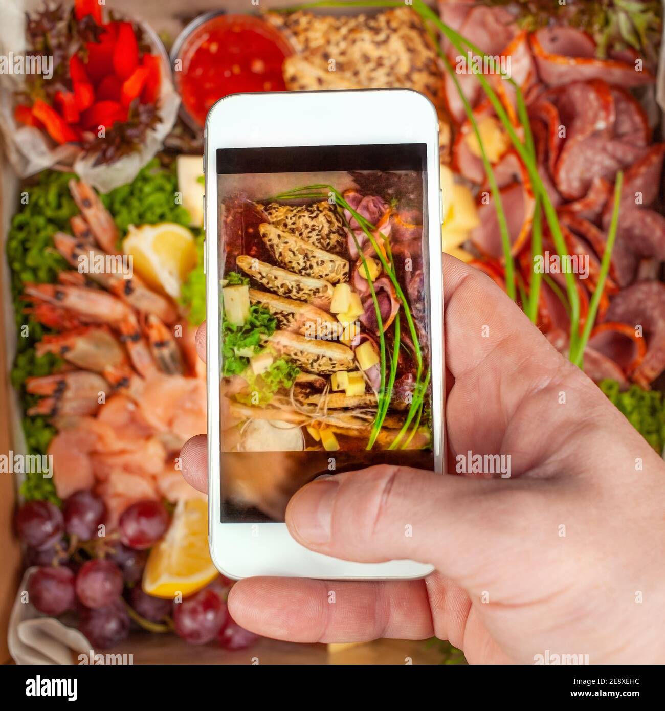 a man takes pictures of food on his phone. Shrimp, snack, fruit, meat ...