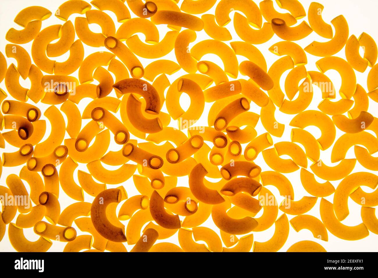 Pasta shapes in vibrant yellow colors scattered on a bright background ...