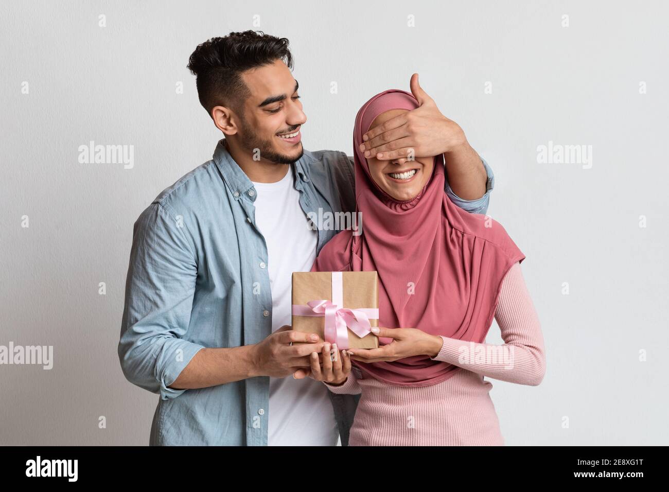 Romantic arab man covering eyes of his muslim wife and giving present ...
