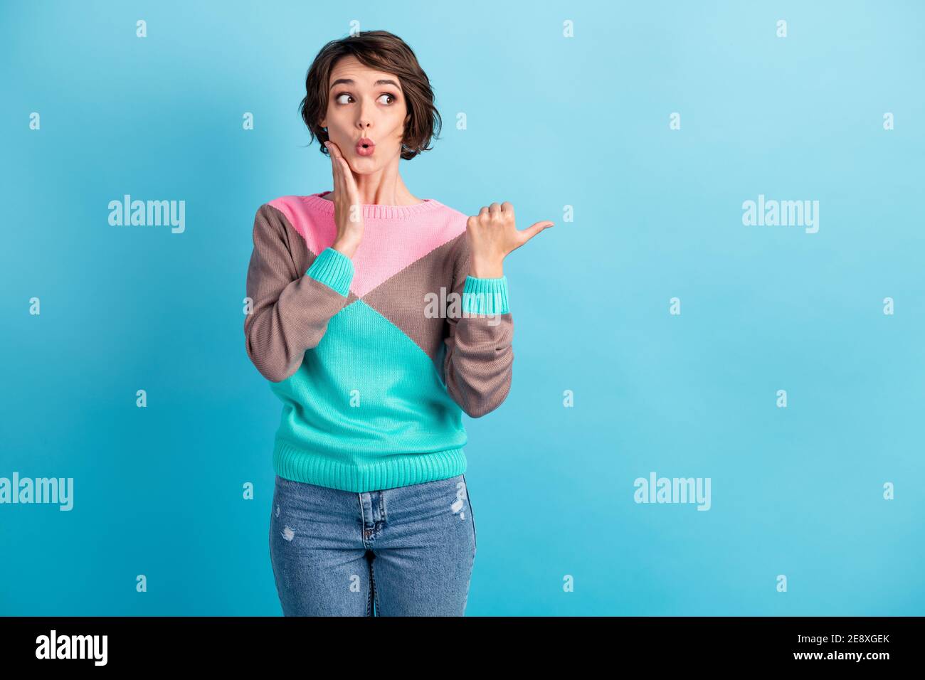 Photo portrait of woman pointing thumb looking at blank space touching ...