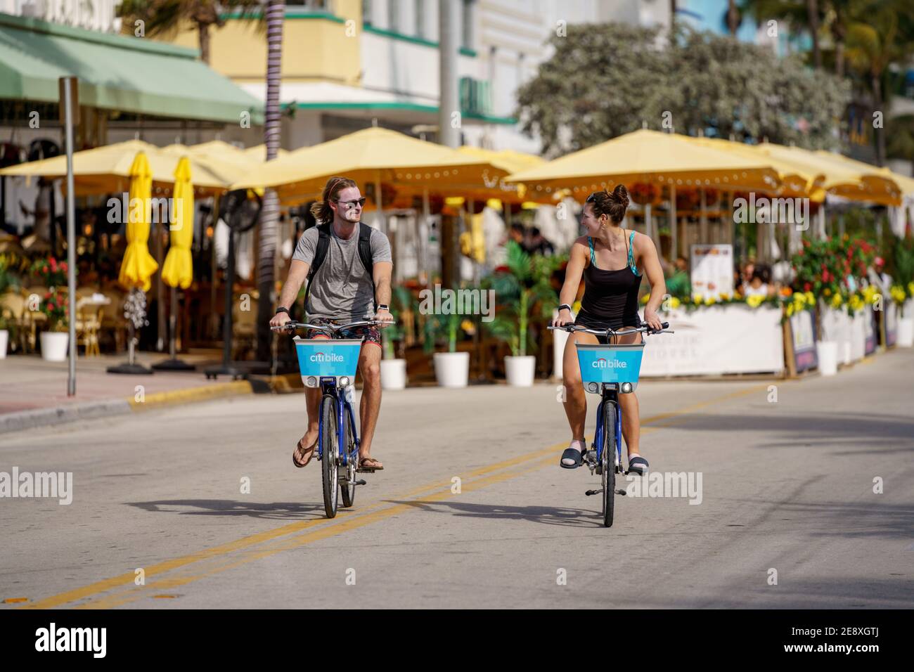 Man and woman riding bikes in Miami Beach street photography Stock ...