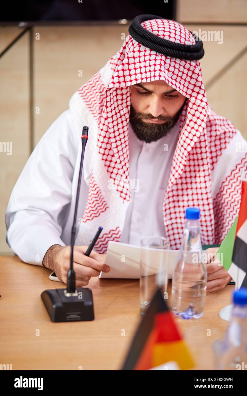 arabic sheikh man wearing traditional emirates clothes sits at desk on ...
