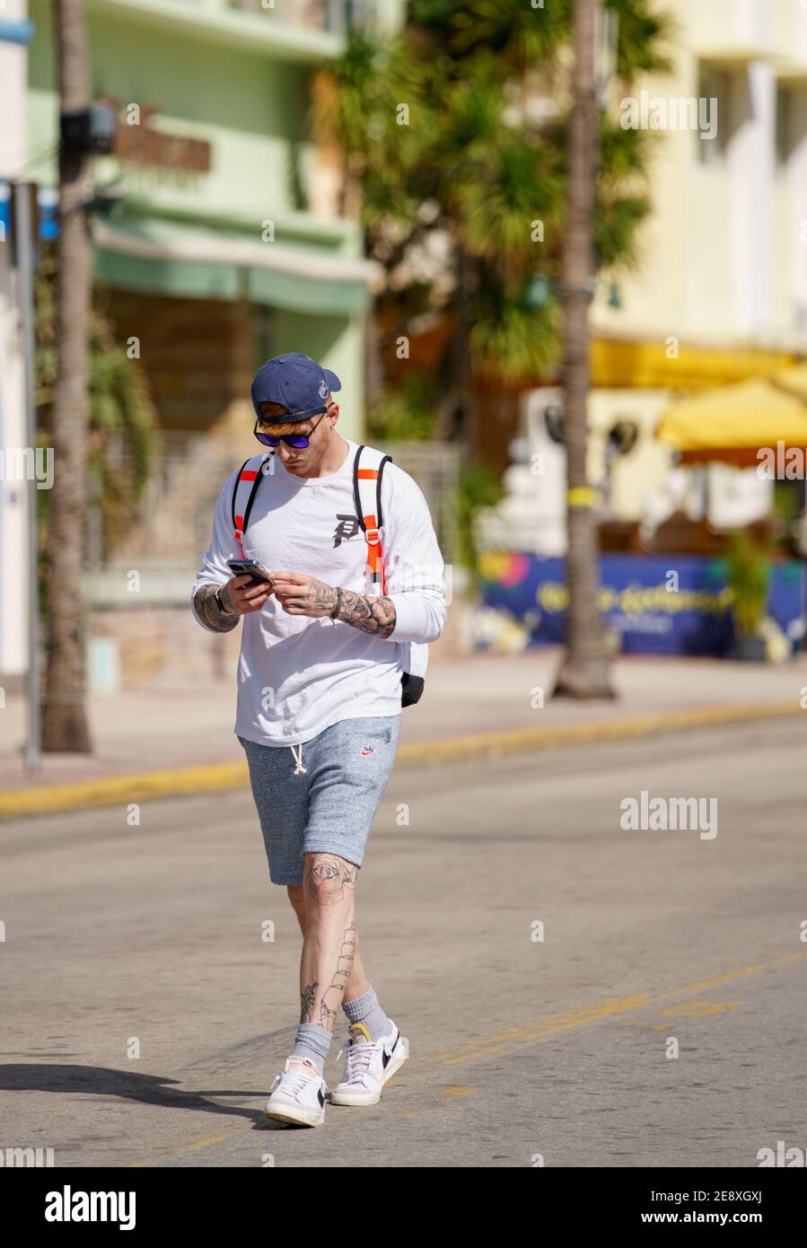 Man walking and looking down at this phone Miami Beach street ...