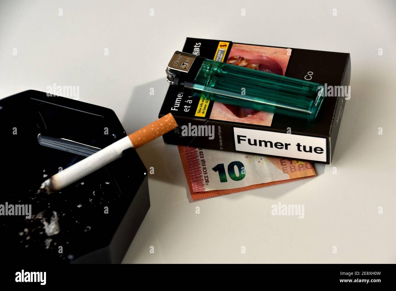 In this photo illustration a 10 euro bill under a cigarette packet and ...