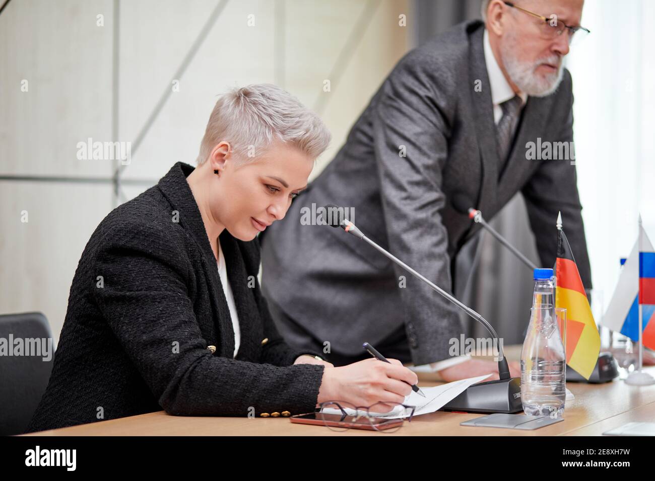 concentrated serious female in suit at conference, listening to talks ...