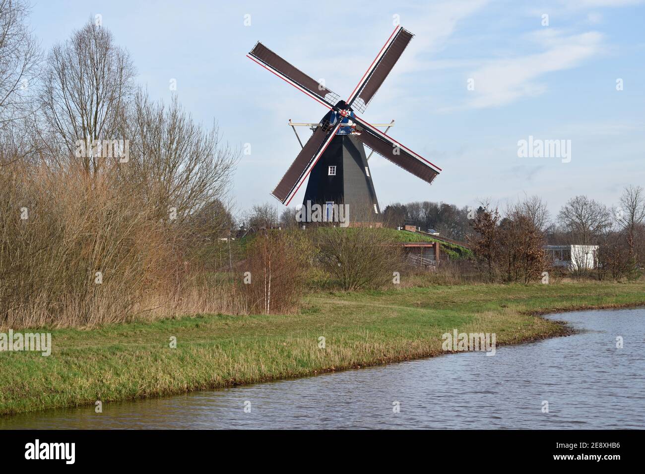 Beautiful Dutch windmill looking over a relaxing canal under a blue ...