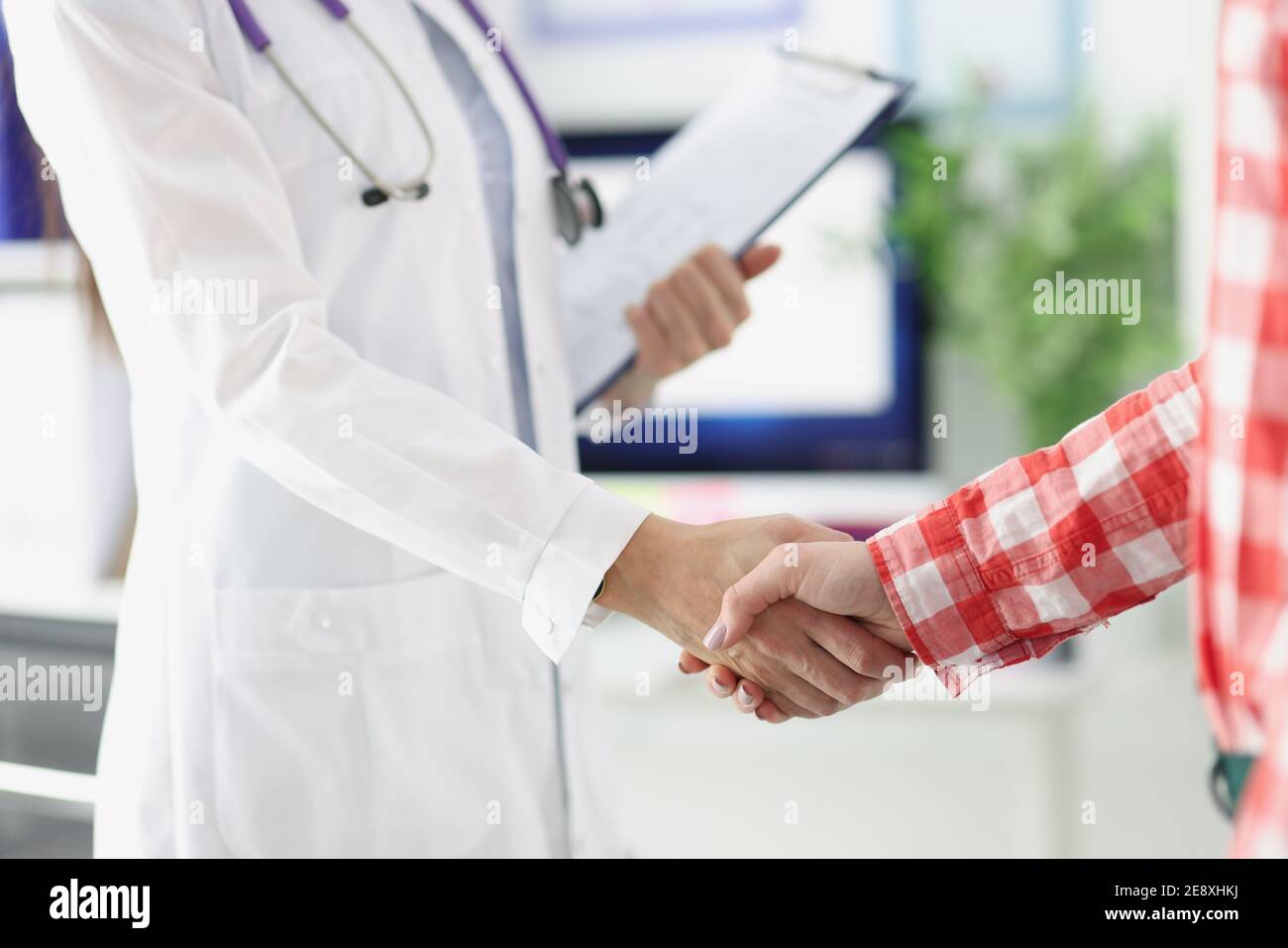 Doctor holding documents and shaking patients hand in clinic Stock ...