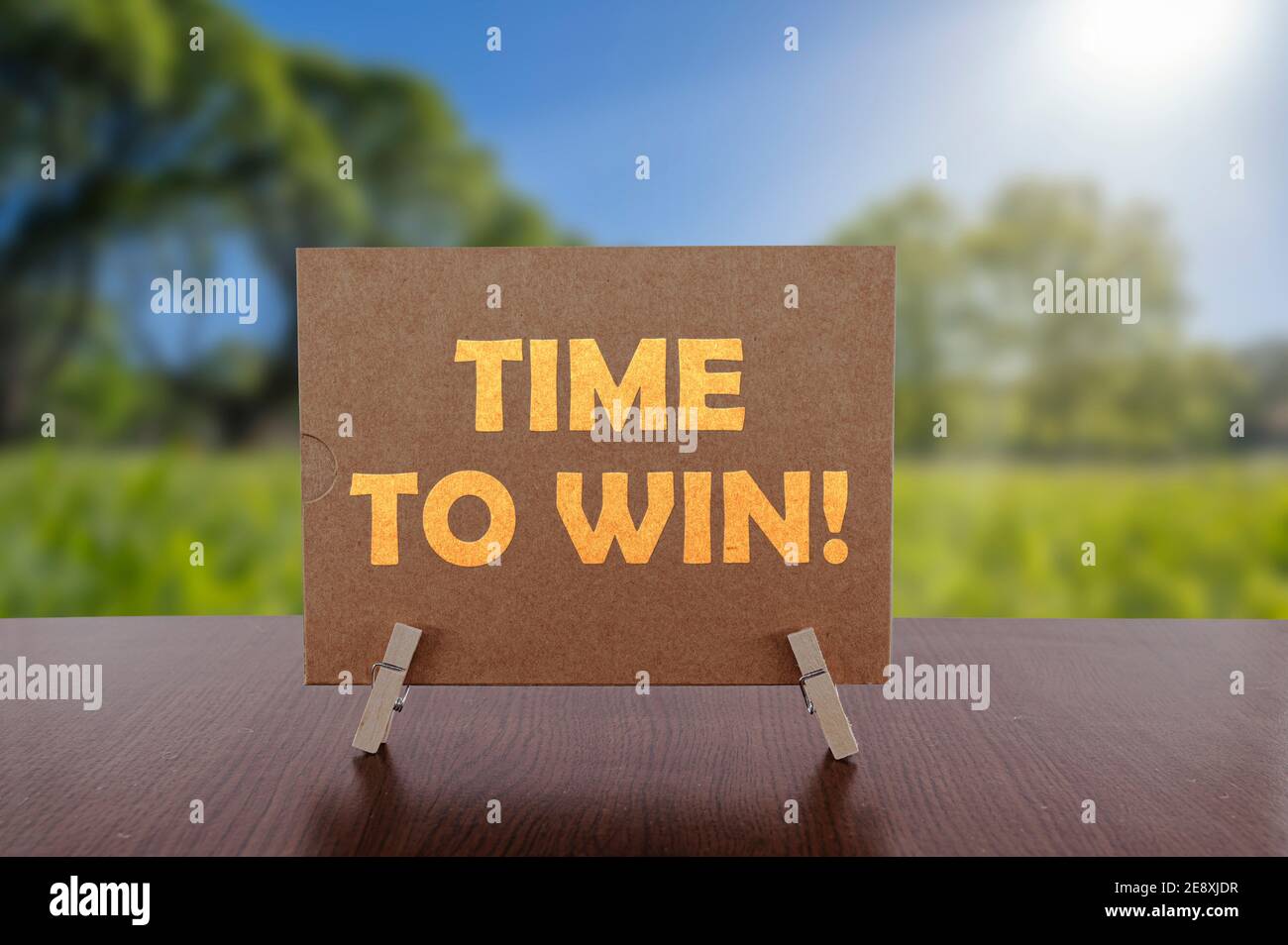 Time to win text on card on the table with sunny green park background ...