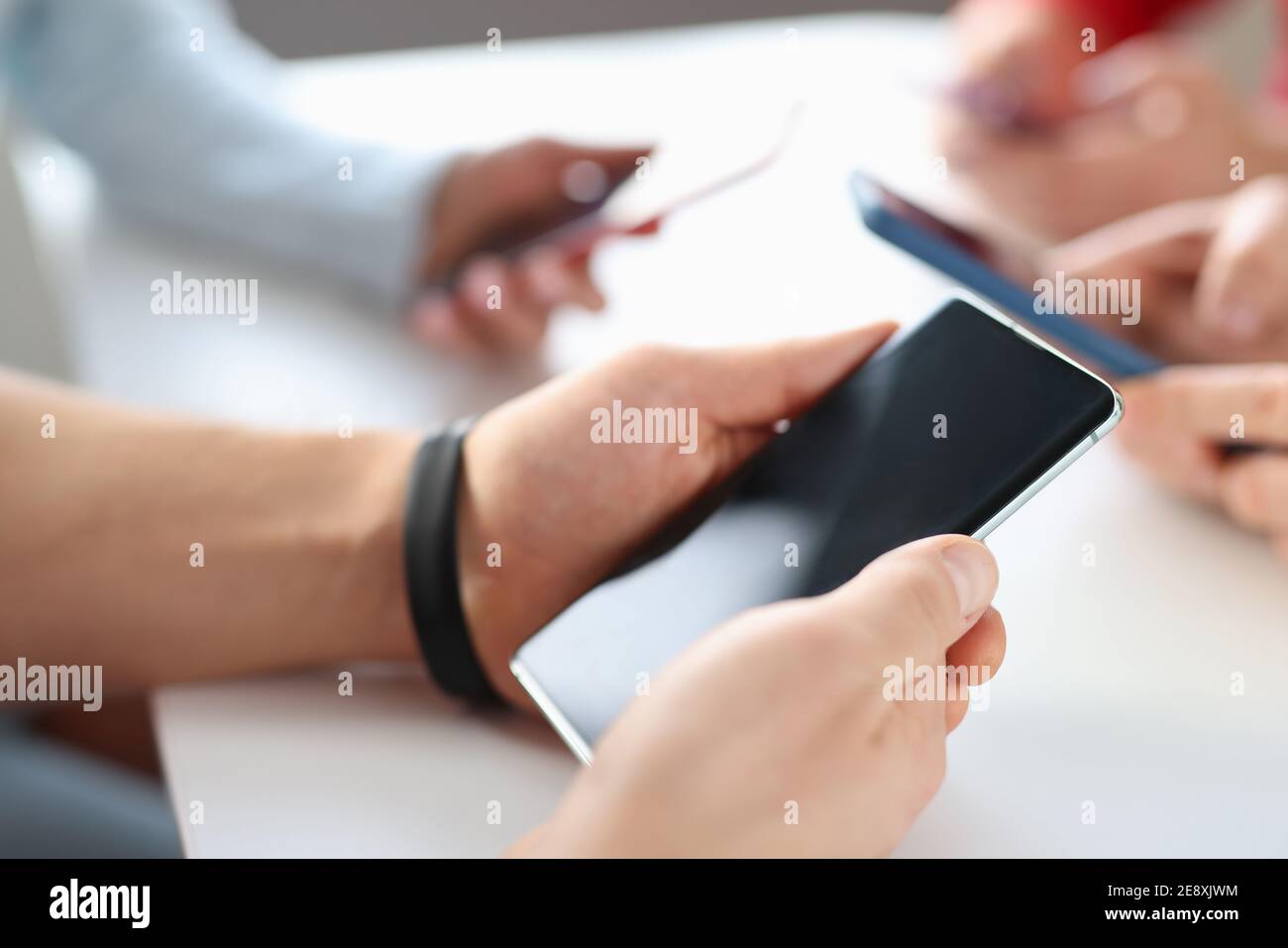 Group of people holding mobile phones at table closeup Stock Photo - Alamy