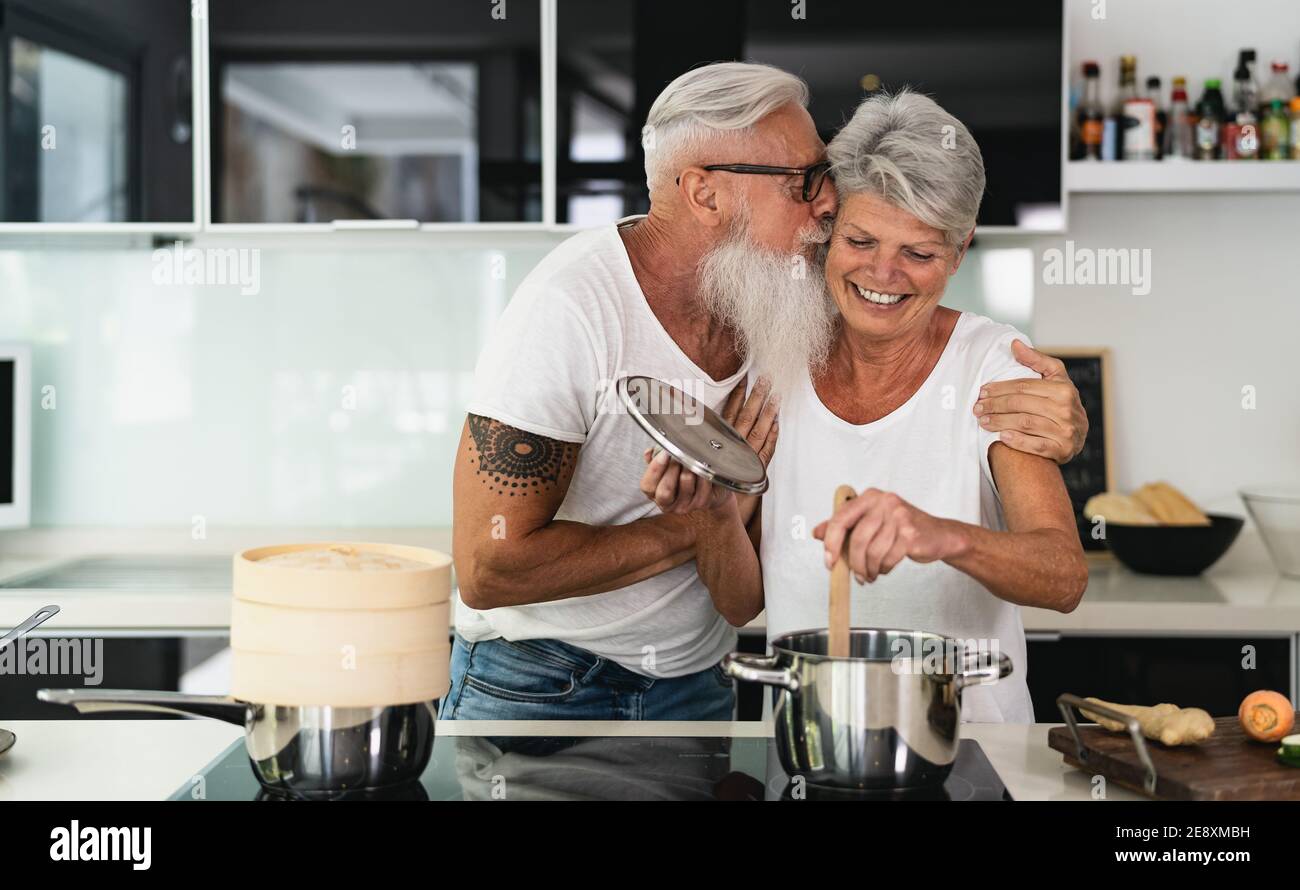 Happy senior couple having fun cooking together at home - Elderly ...