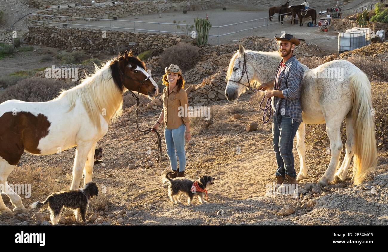Happy couple having fun with horses inside stable - Young farmers ...